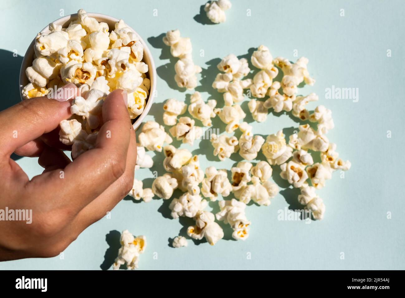 Hand taking salt popcorn from craft paper cup Stock Photo - Alamy