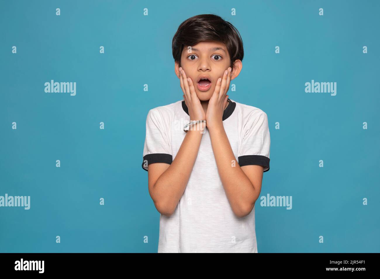 Portrait of shocked boy standing against blue background Stock Photo ...