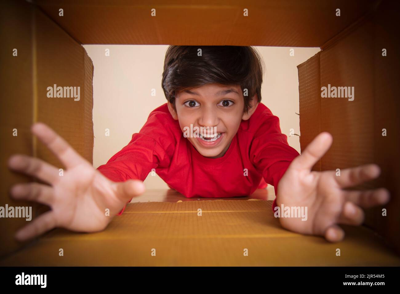 Portrait of cheerful boy looking through a carton box Stock Photo - Alamy