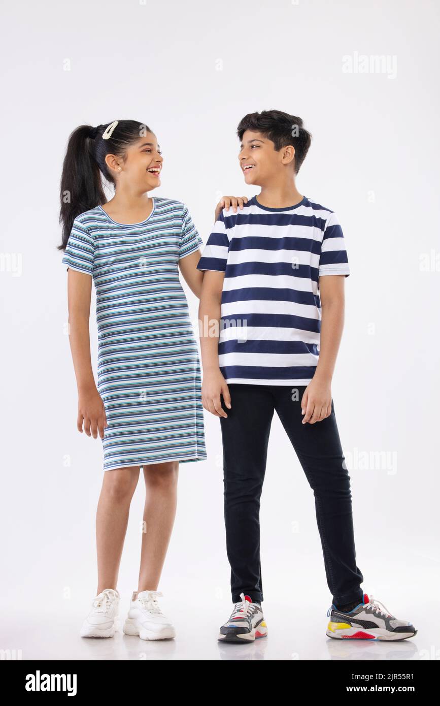 Portrait of two cheerful children standing against white background ...