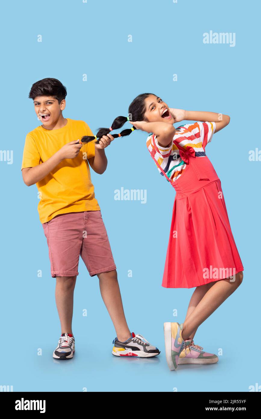 Portrait of brother pulling braid of his sister Stock Photo - Alamy