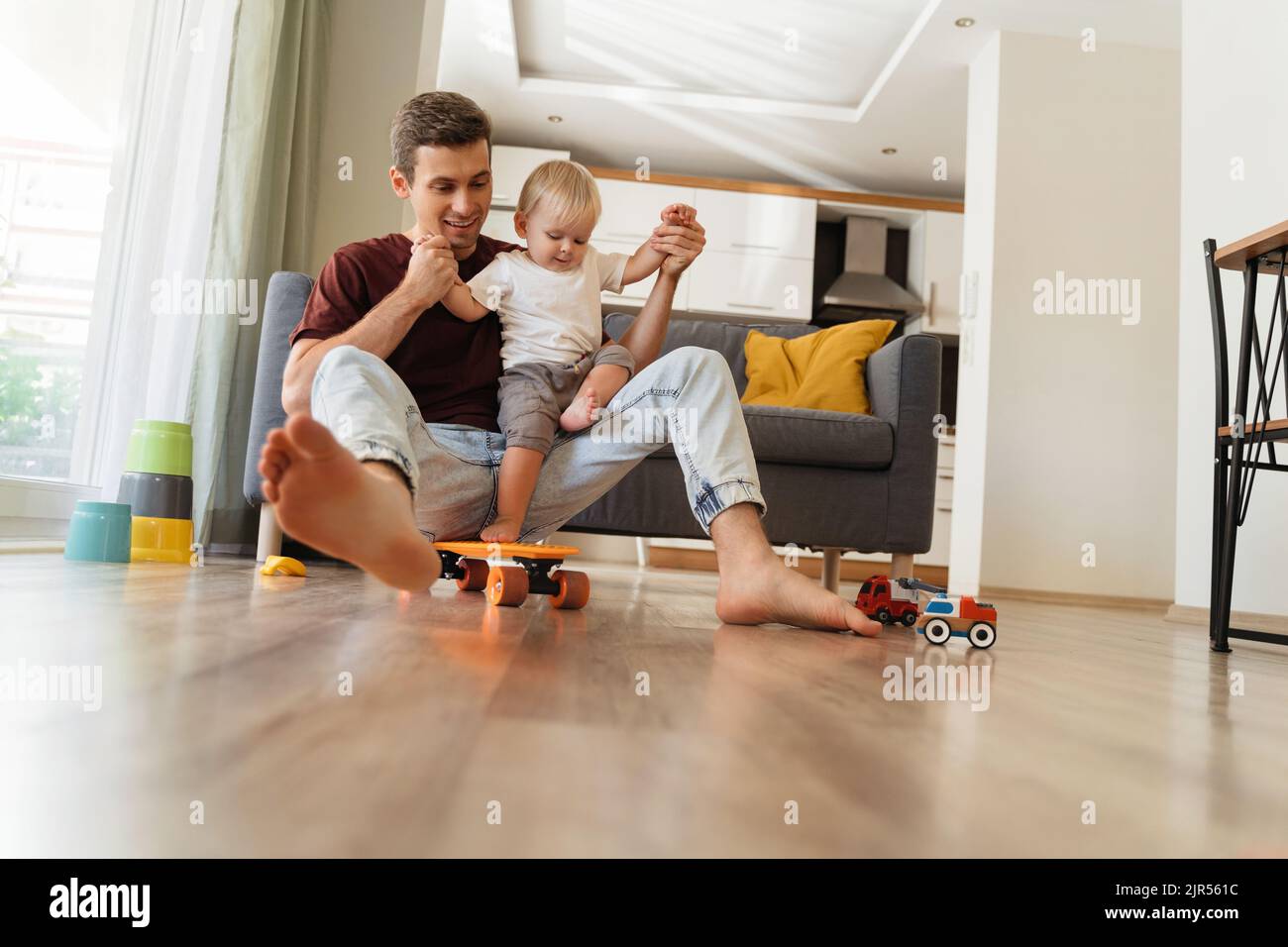 Young father playing with his little baby boy in living-room, holding ...