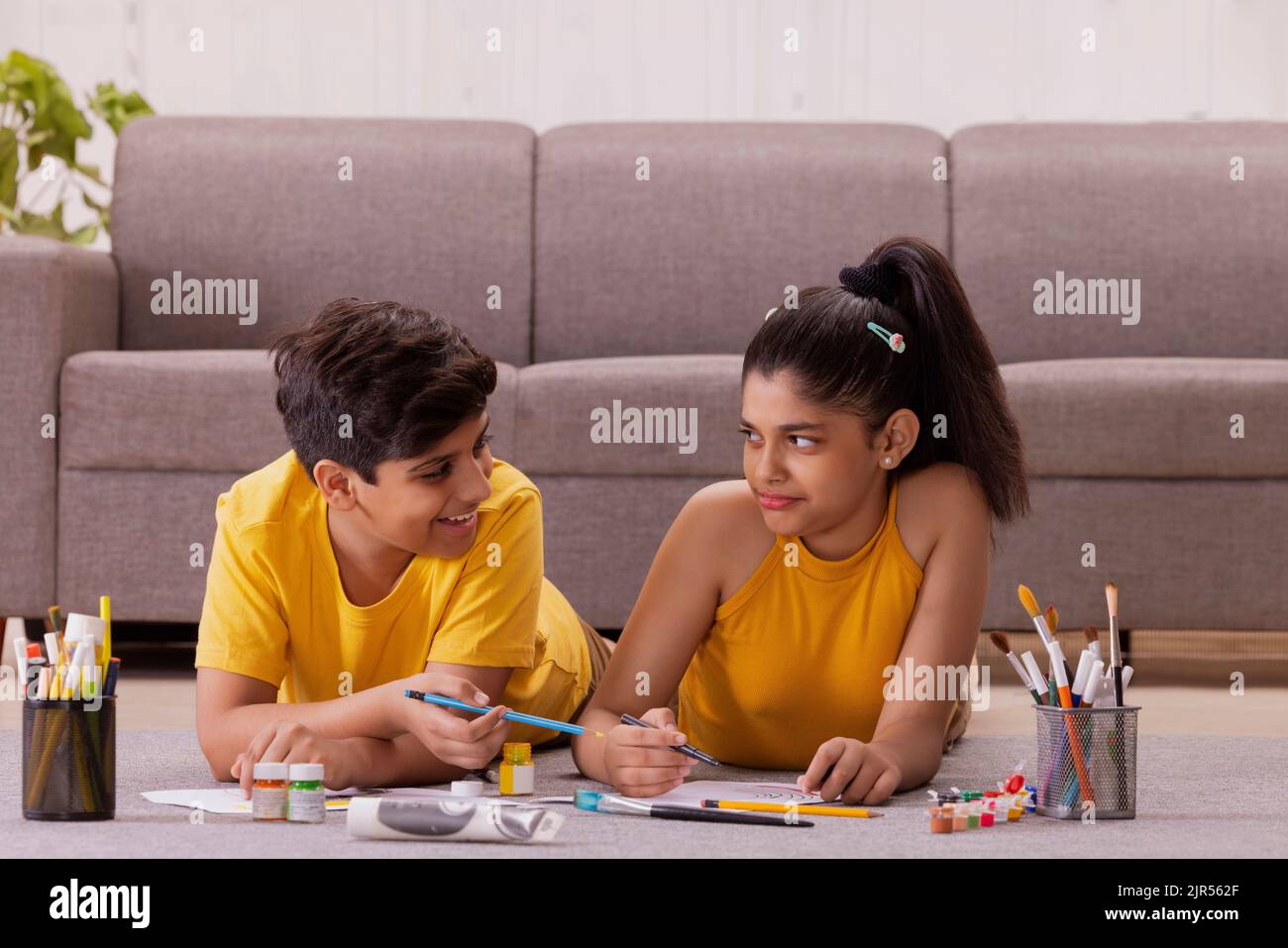 Boy and girl drawing while lying down on floor in at home Stock Photo ...