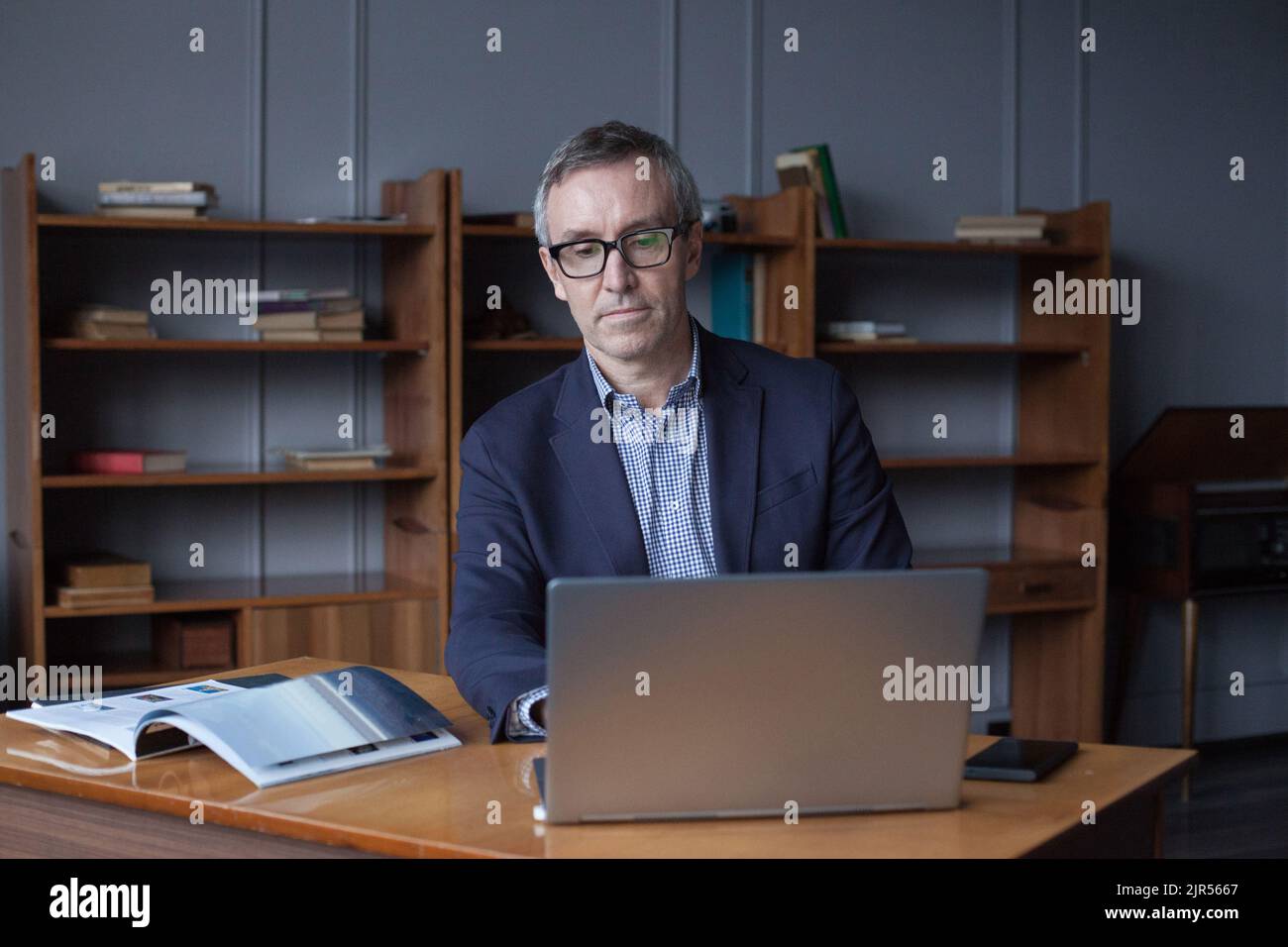 Serious grey-haired male working at laptop, focused businessman used ...