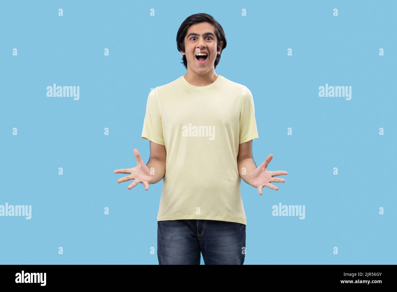 Portrait of an excited teenage boy gesturing while standing against ...