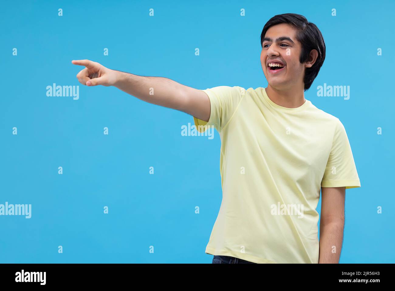 Portrait of a teenage boy pointing away against blue background Stock ...