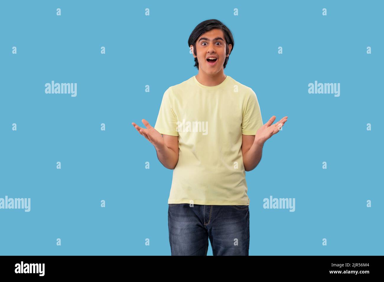 Portrait of an excited teenage boy gesturing while standing against ...