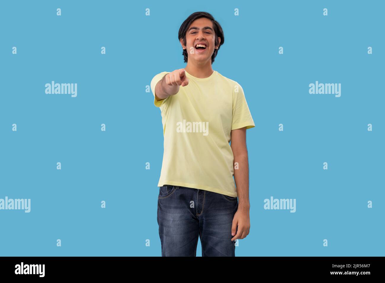 Portrait of a teenage boy pointing towards camera while standing ...