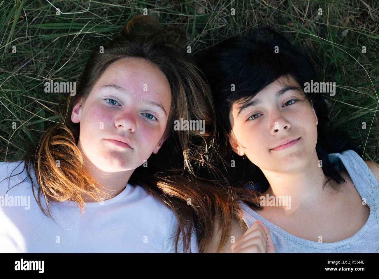 From above of the two girls lying on the green grass Stock Photo - Alamy