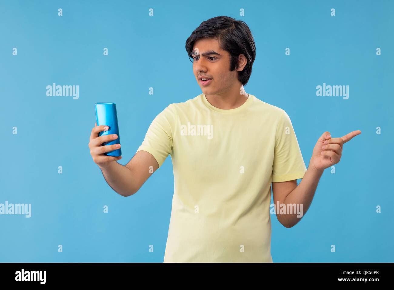 Teenage boy having video call on Smartphone against blue background ...