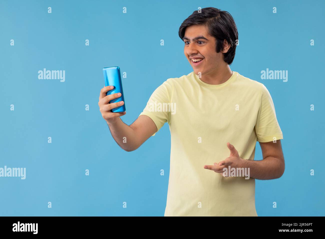 Teenage boy having video call on Smartphone against blue background ...