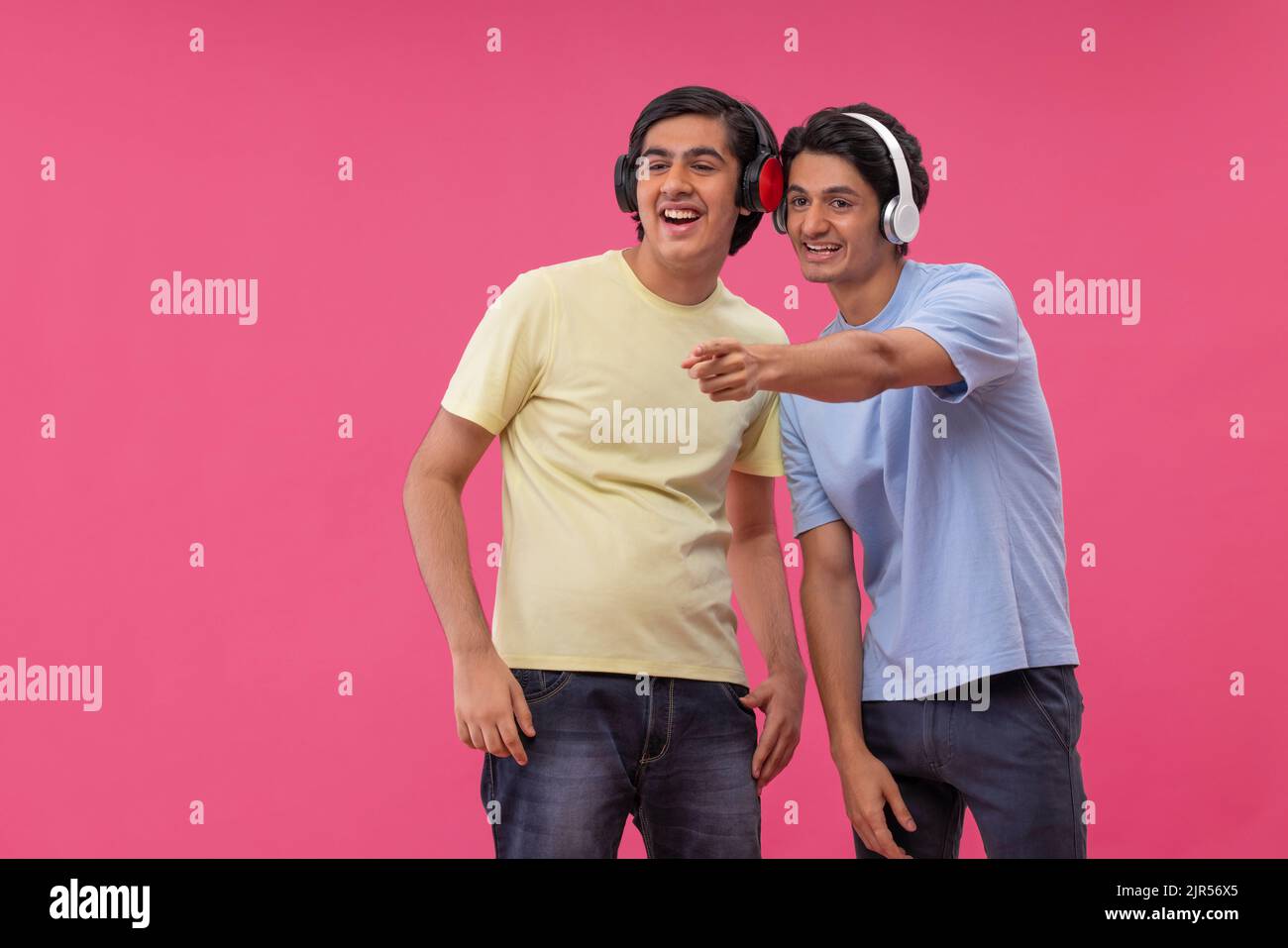 Two happy friends listening to music against pink background Stock ...