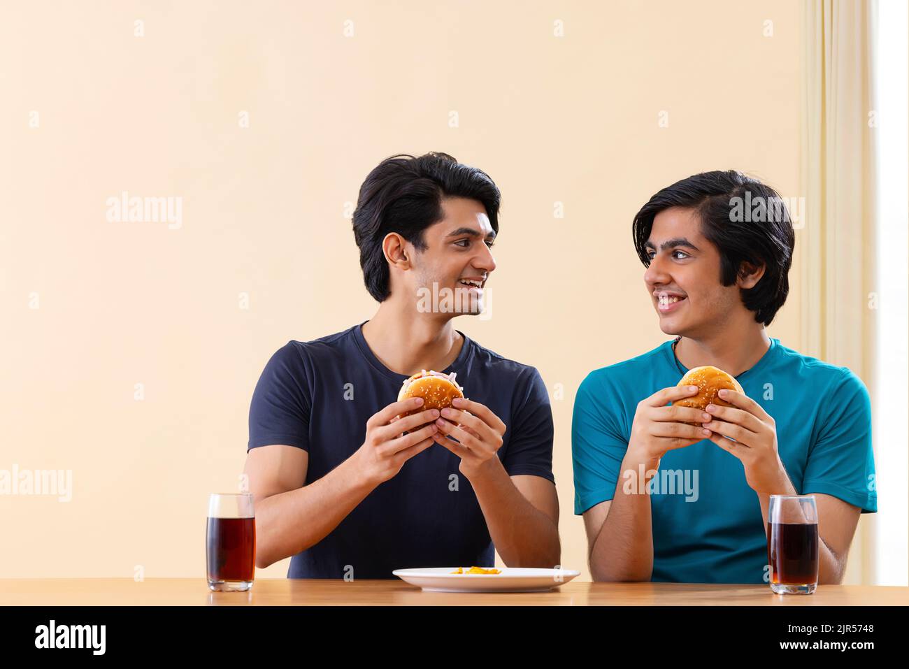 Portrait of teenage boys eating burgers together Stock Photo - Alamy