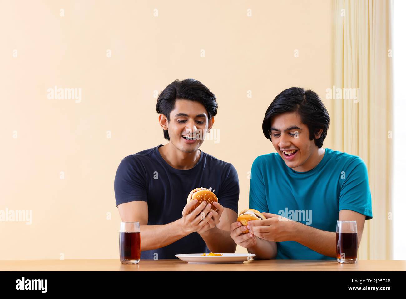 Portrait of teenage boys eating burgers together Stock Photo - Alamy