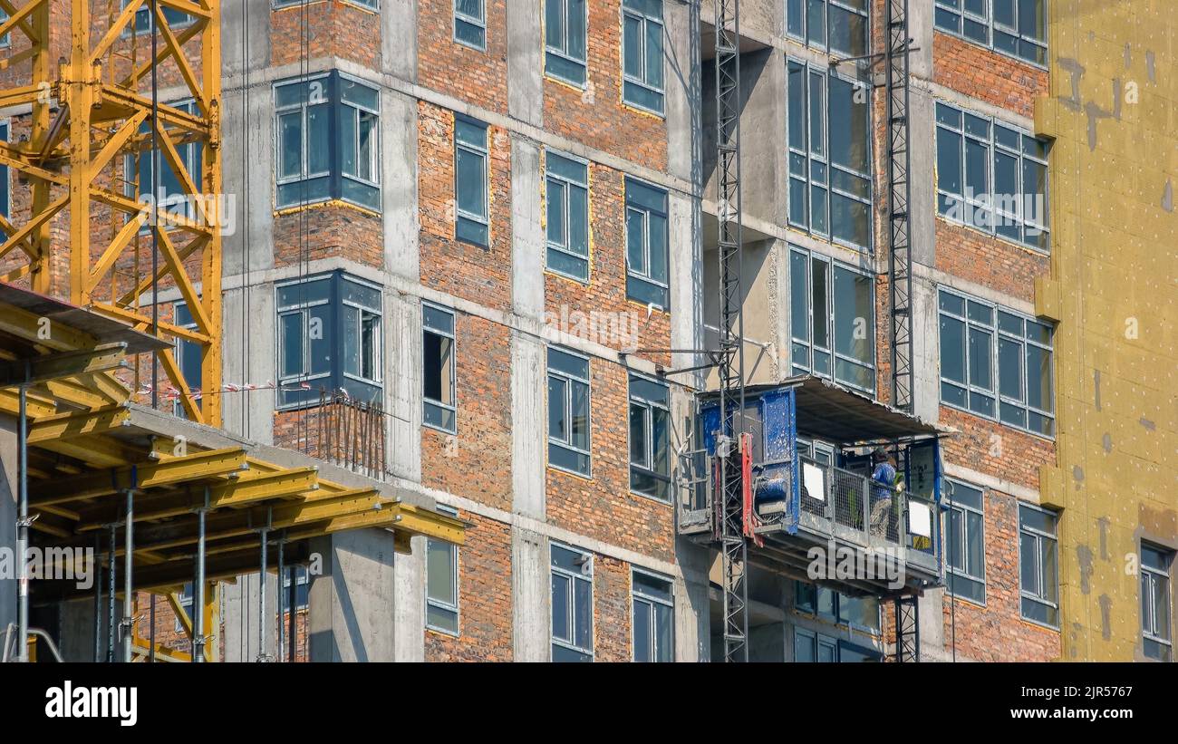 Construction workers moving down on the elevator. Facade with windows ...
