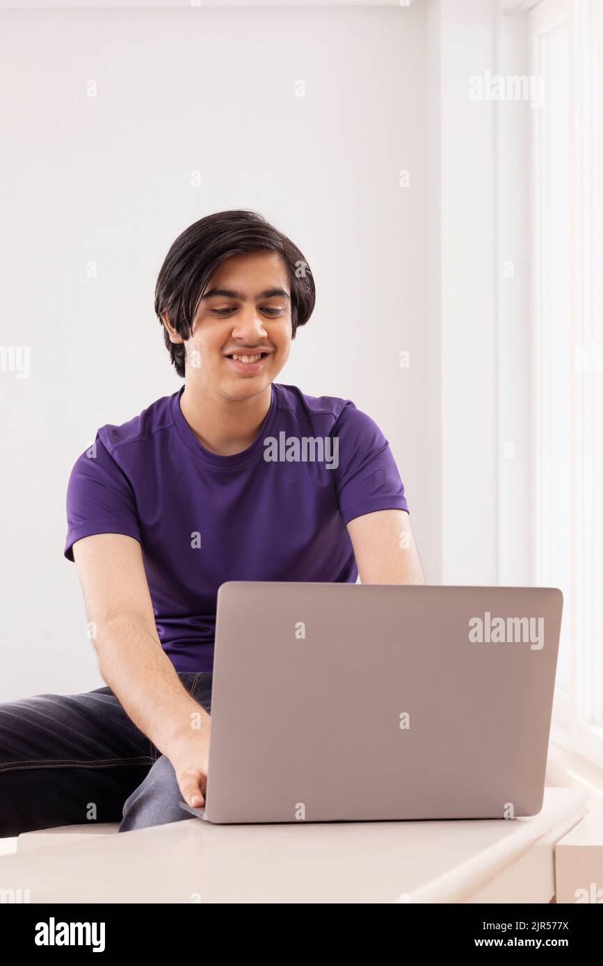 Portrait of teenage boy using laptop against plain background Stock ...