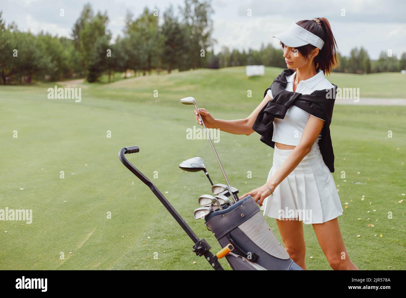 Woman golf player choosing the golf club from the bag outdoors Stock ...