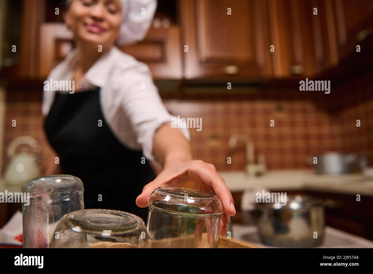 Details: Hand of a blurred smiling woman taking out a glass jar from a ...