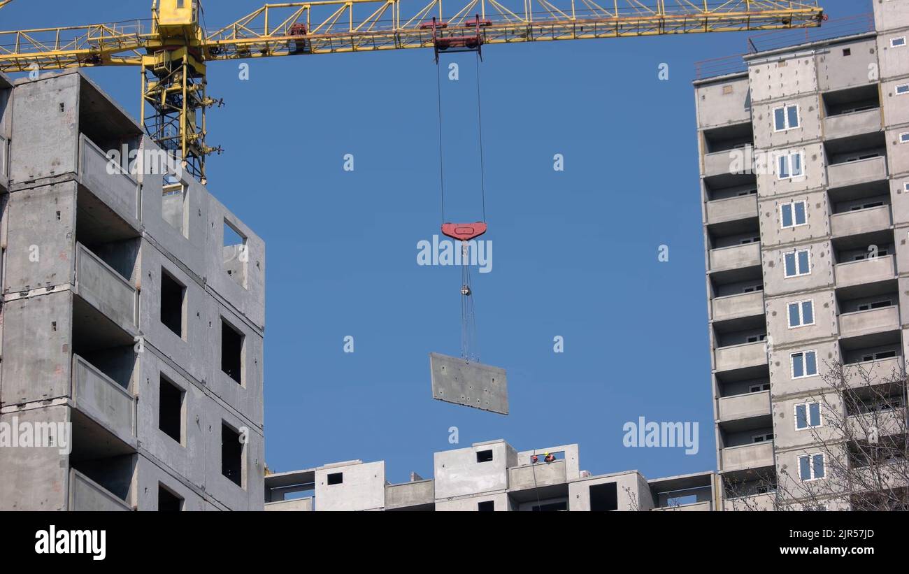 Large construction crane sets up the wall on the building. Building a ...