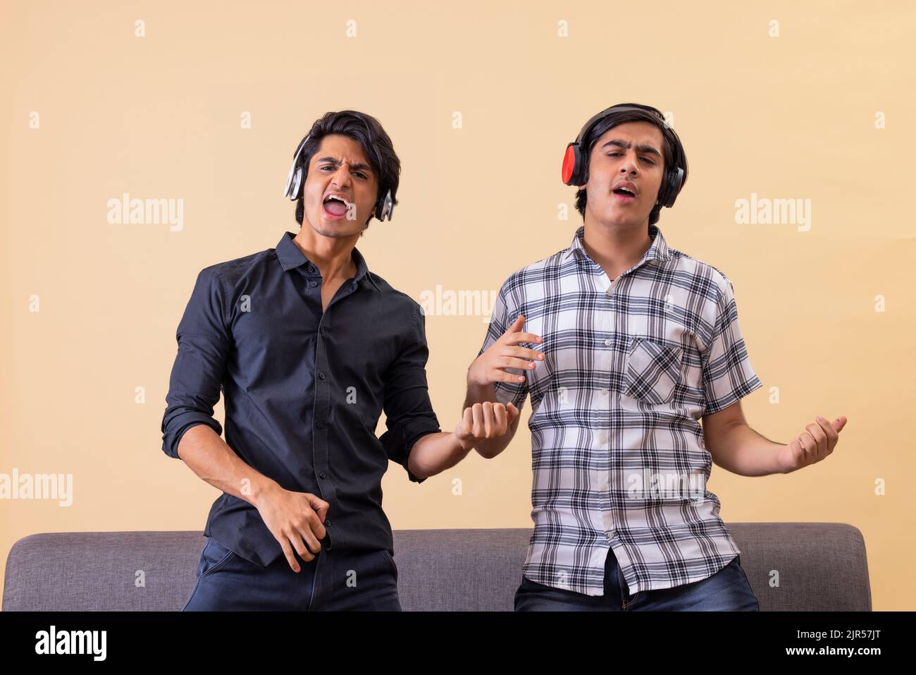 Portrait of two happy teenage boys listening to music and gesturing ...