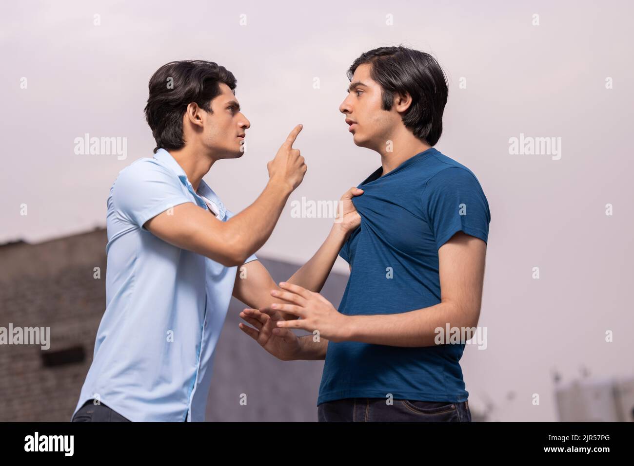 One teenage boy pulling the other by the collar of his shirt against ...