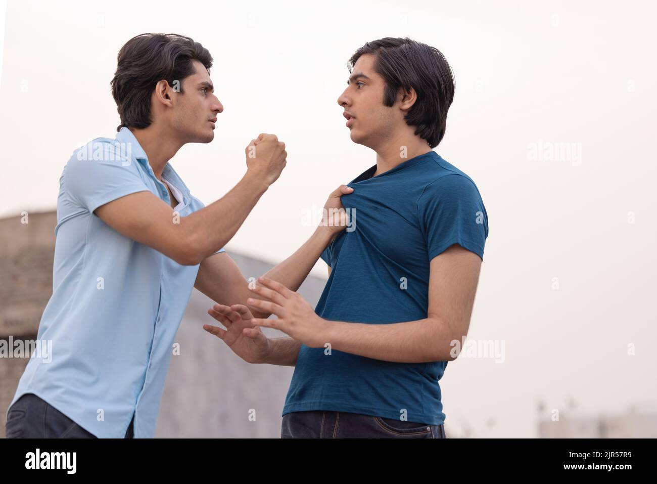 One teenage boy pulling the other by the collar of his shirt against ...