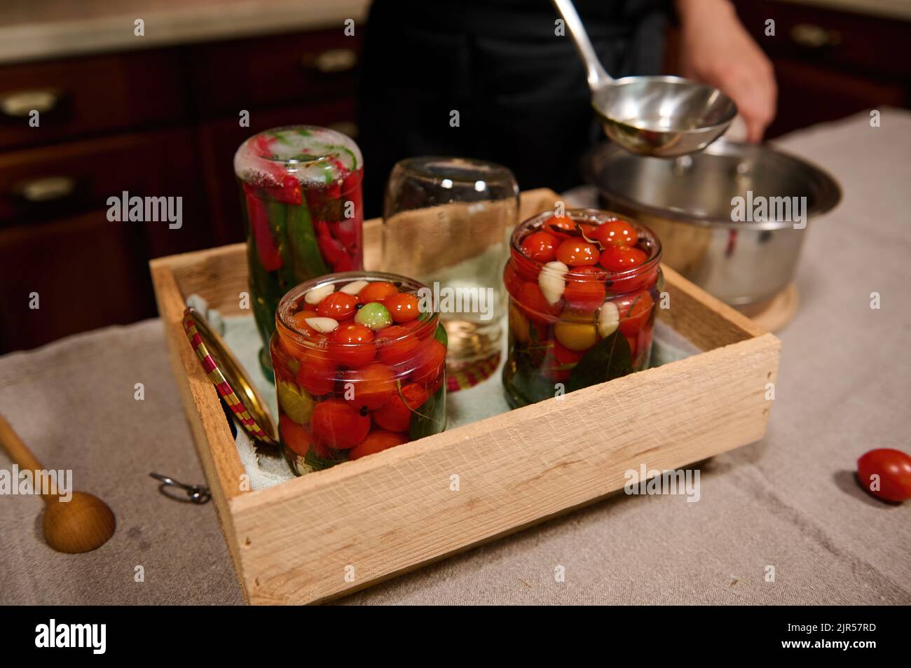 Sterilized cans for canning with cherry tomatoes and chef using soup ...