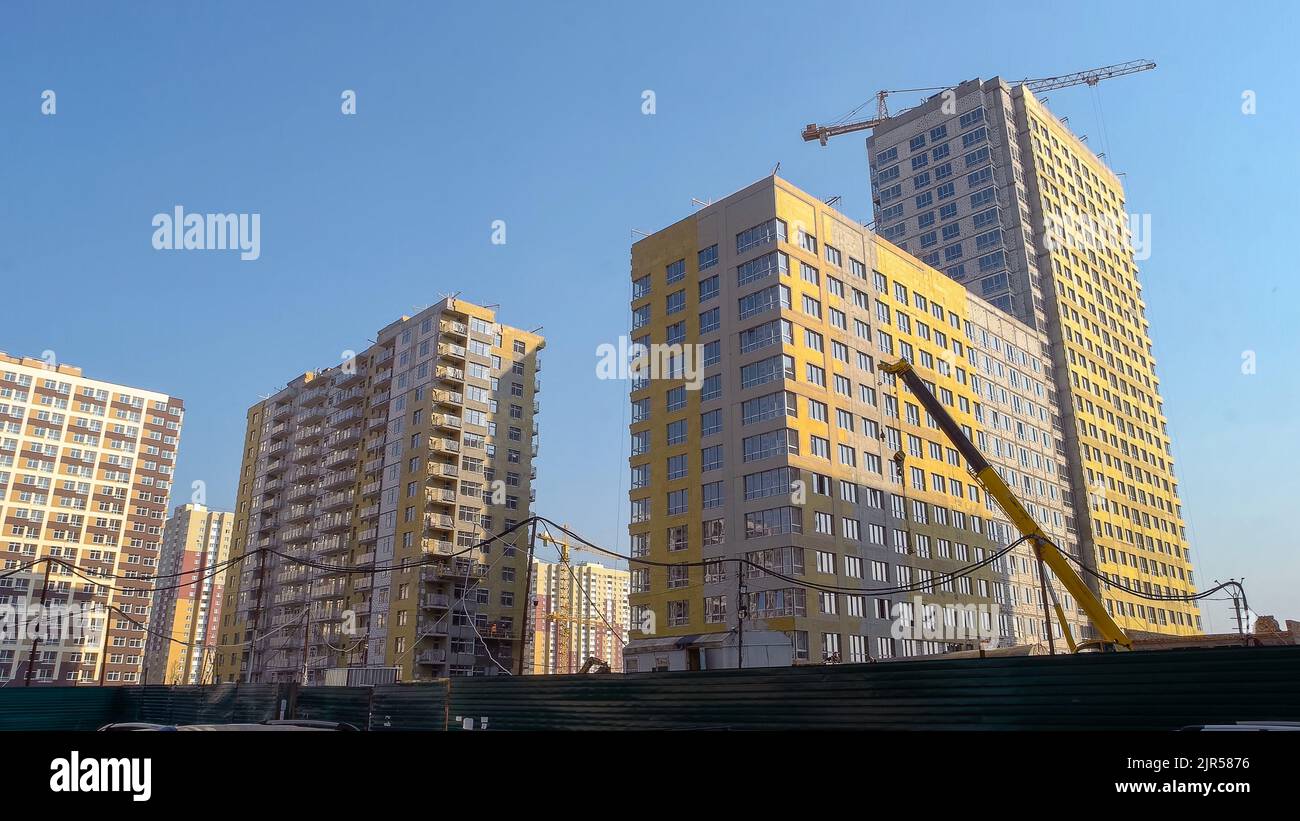 Many high-rise buildings and yellow construction crane. Blus sky ...