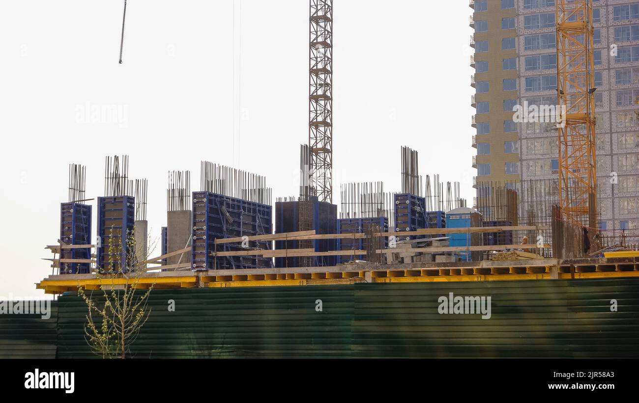 Crane lifts up metal frame on the construction site. Worker wearing ...