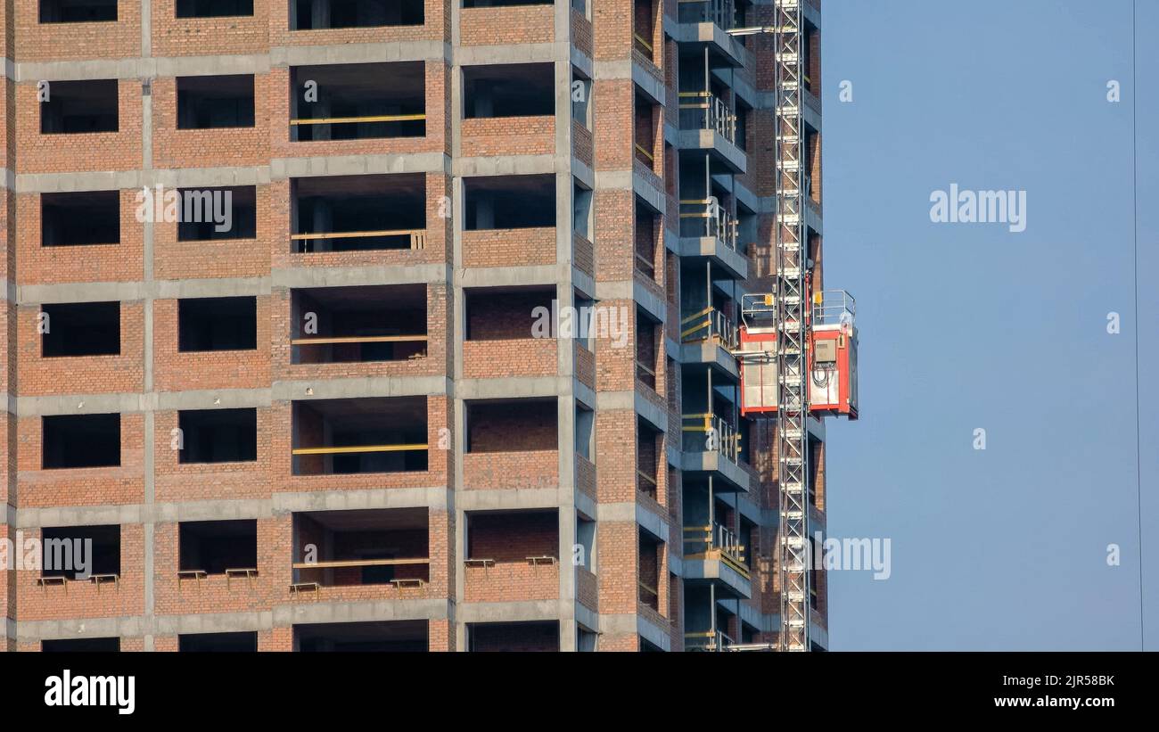 Building under construction with an elevator lift. Workers moving down ...