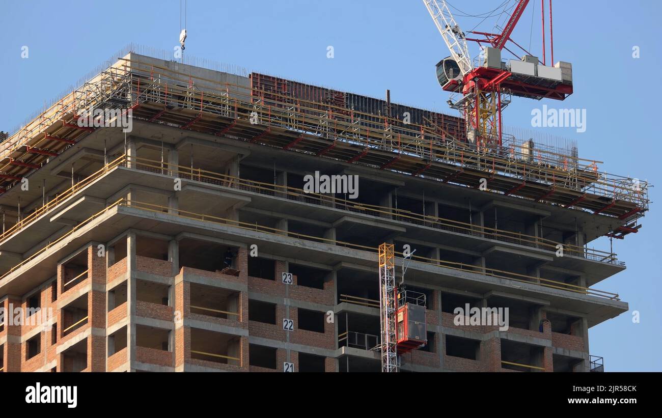 Building constriction site with scaffolding and crane. Red crane ...