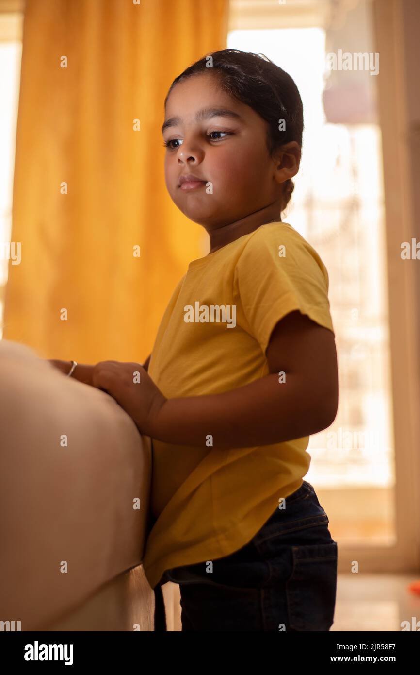 Portrait of cute little girl looking elsewhere while standing at home ...