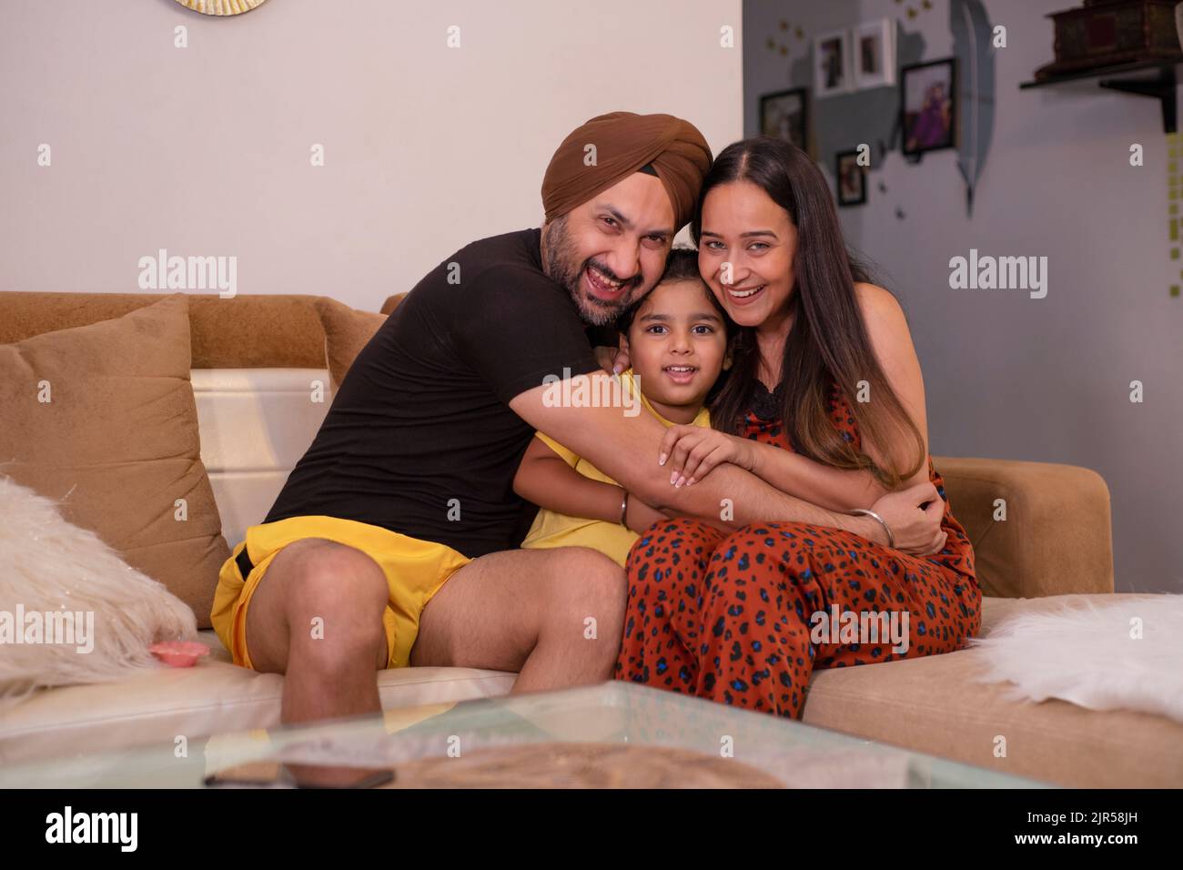 Portrait of happy Sikh family sitting on sofa in living room Stock ...