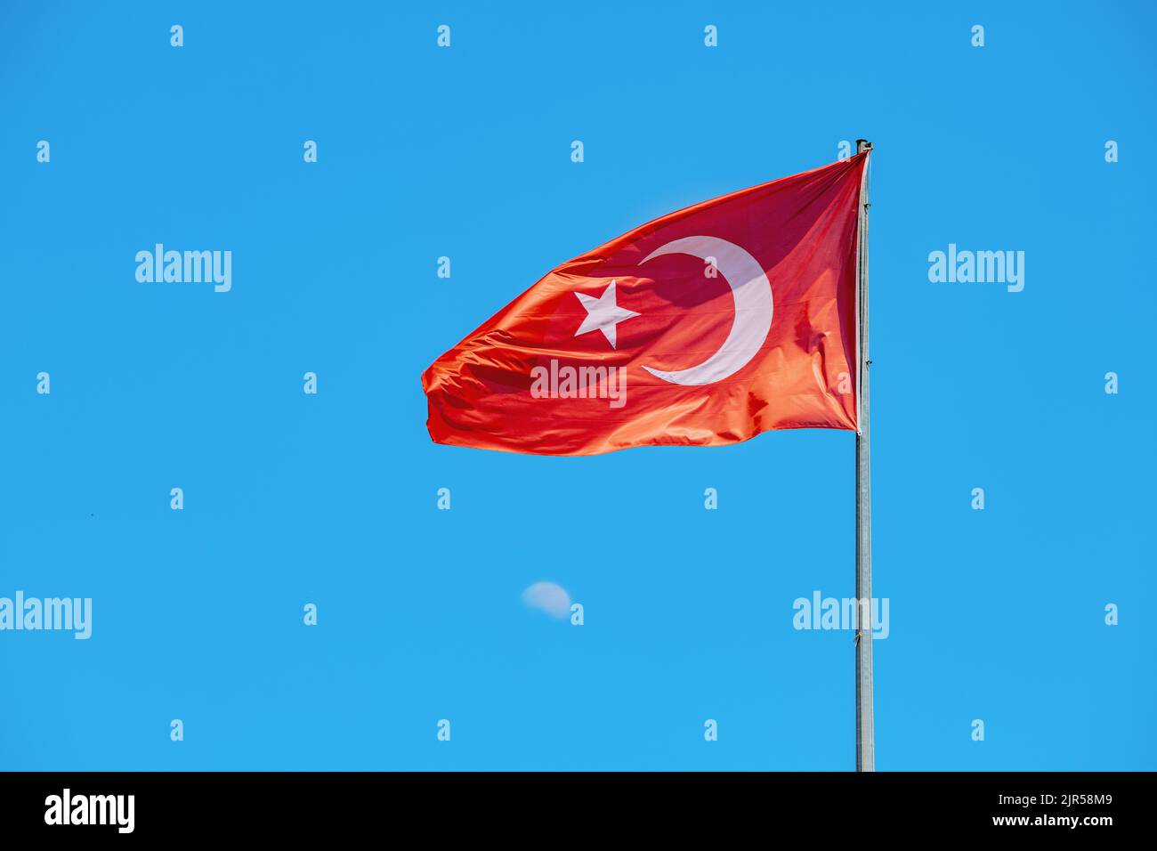 The national Turkish flag on a blue sky background with moon crescent ...