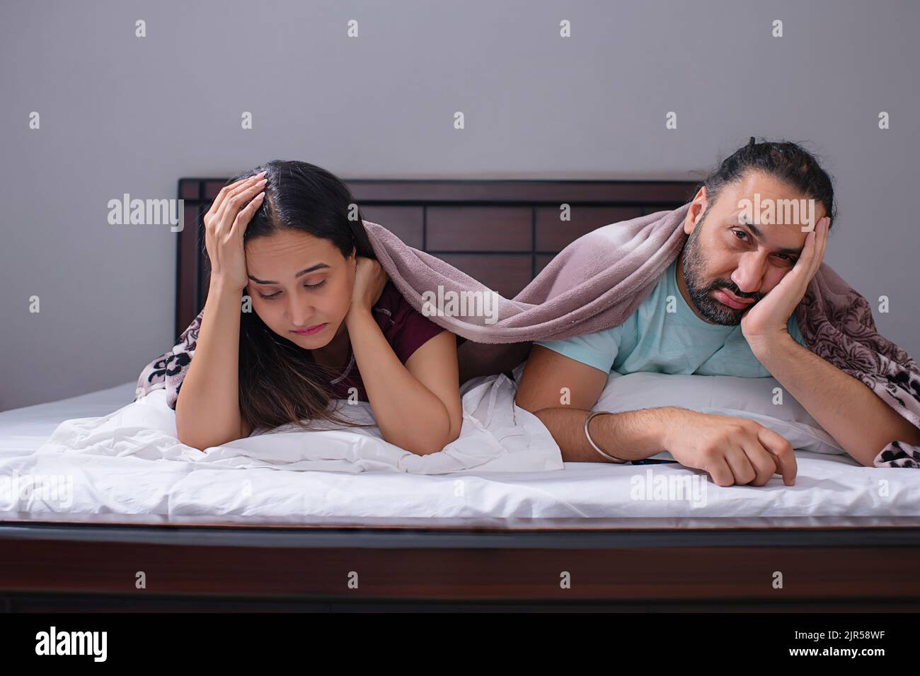 Tired couple lying together under blanket on bed Stock Photo - Alamy