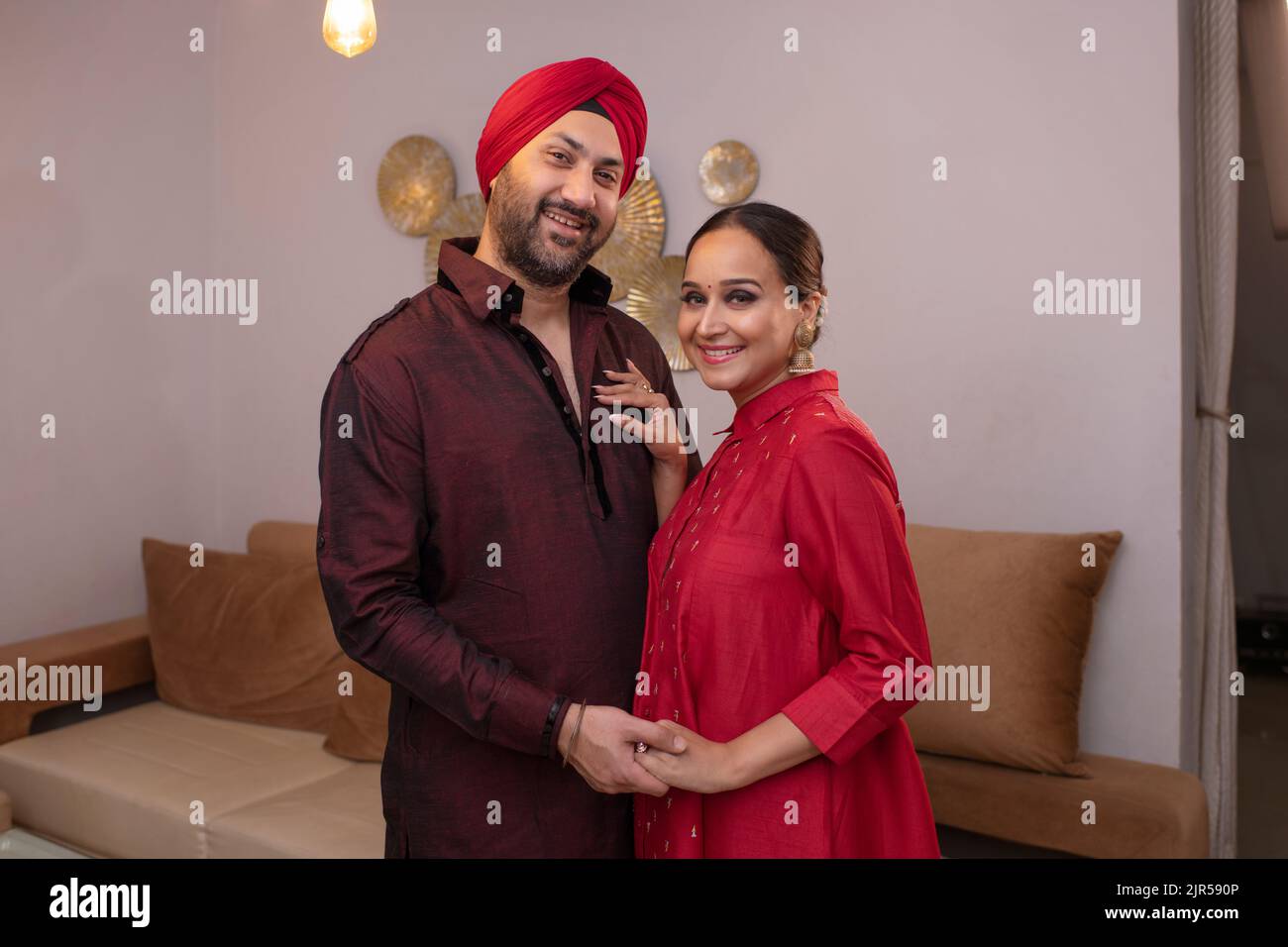 Portrait of a happy Sikh couple standing together in living room Stock ...