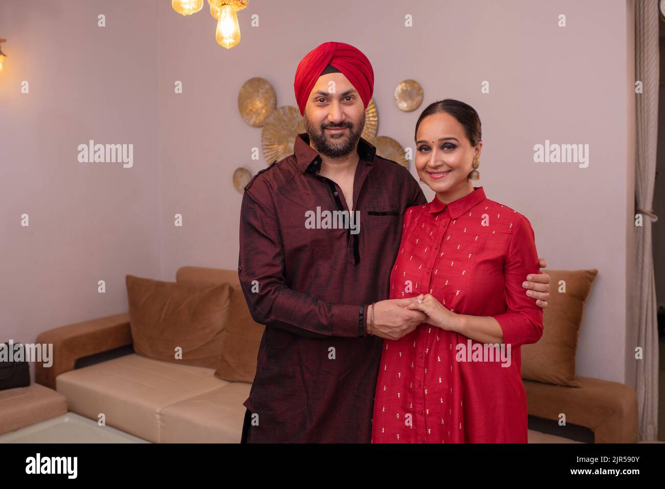 Portrait of a happy Sikh couple standing together in living room Stock ...