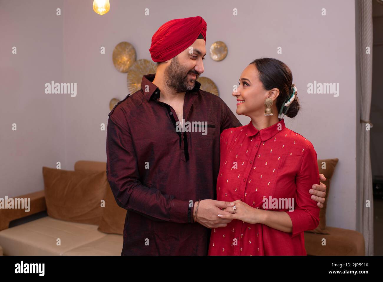 Portrait of a happy Sikh couple standing together in living room Stock ...