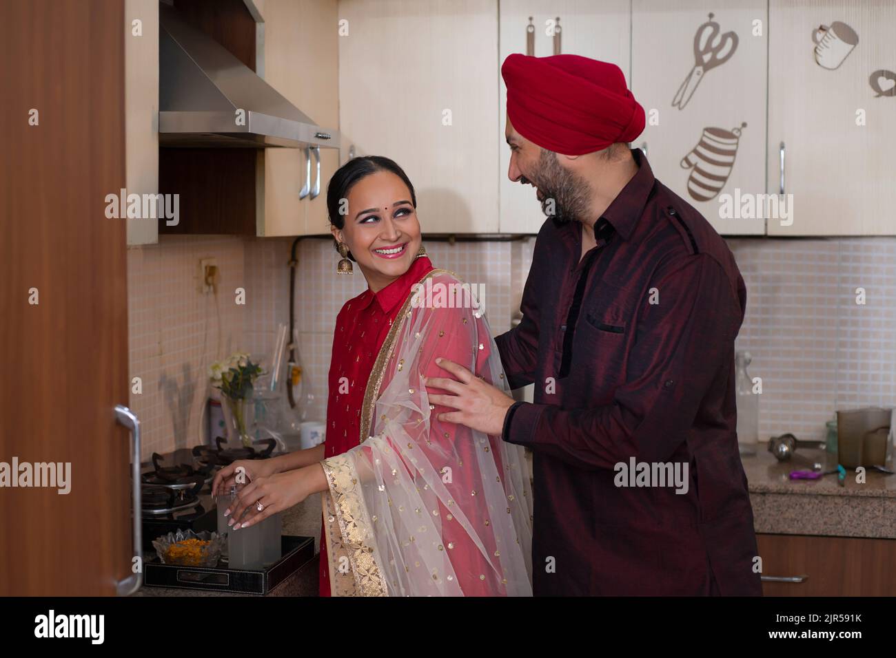 Portrait of a happy Sikh couple standing together in the kitchen Stock ...