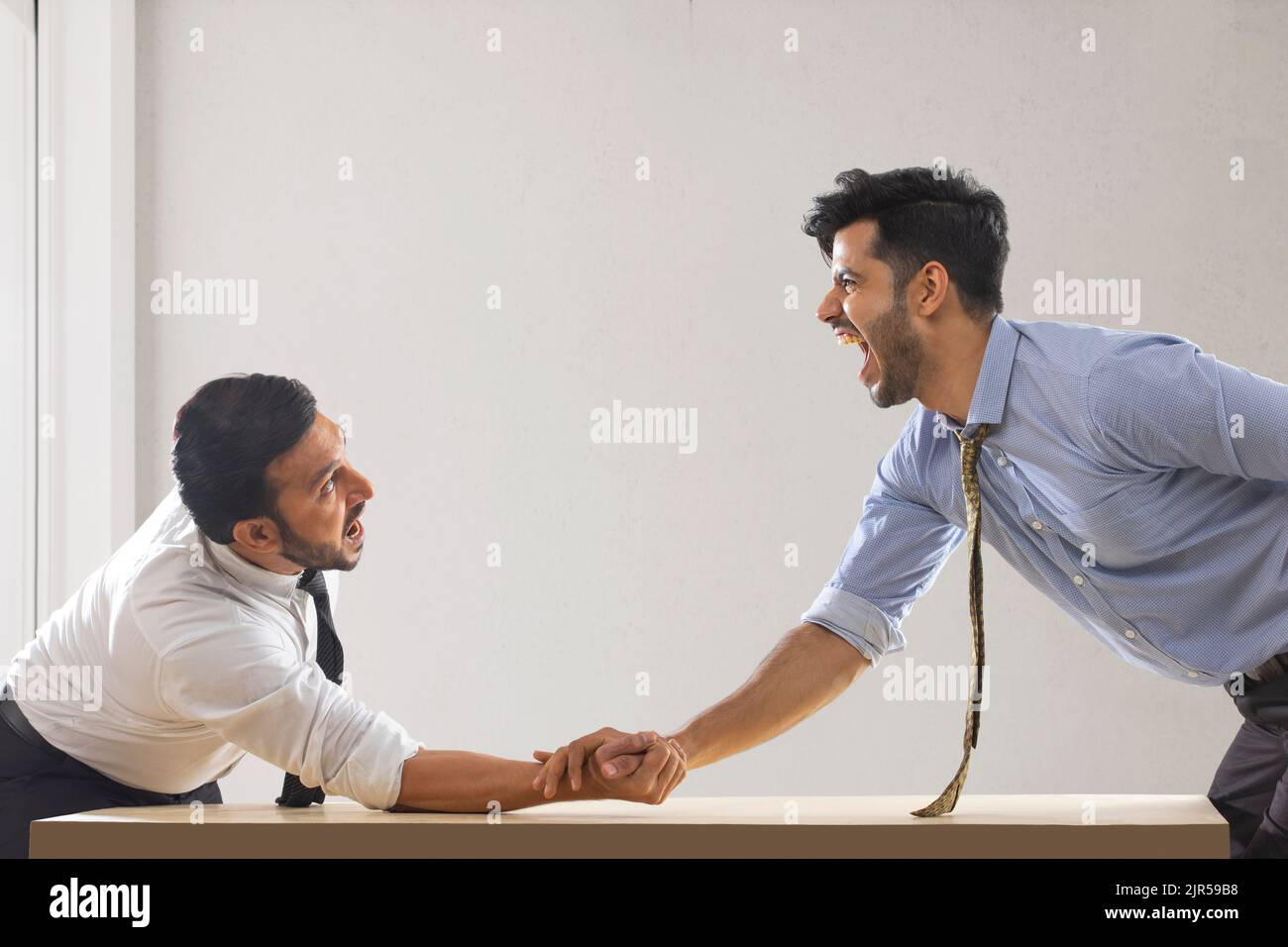 Corporate employees in formal clothing engaged in an arm wrestling ...