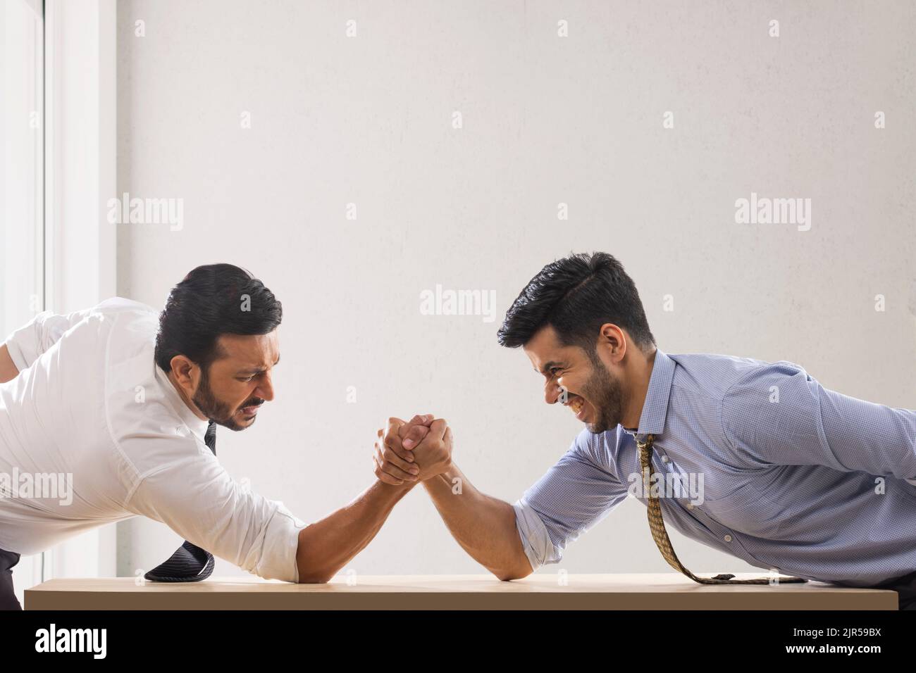 Corporate employees in formal clothing engaged in an arm wrestling ...