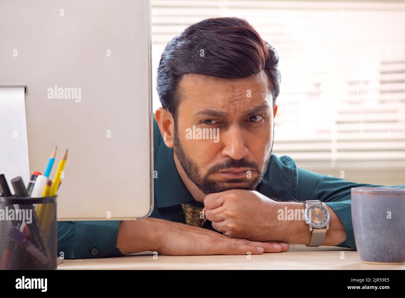 A corporate employee thinking while looking at desktop screen in office ...