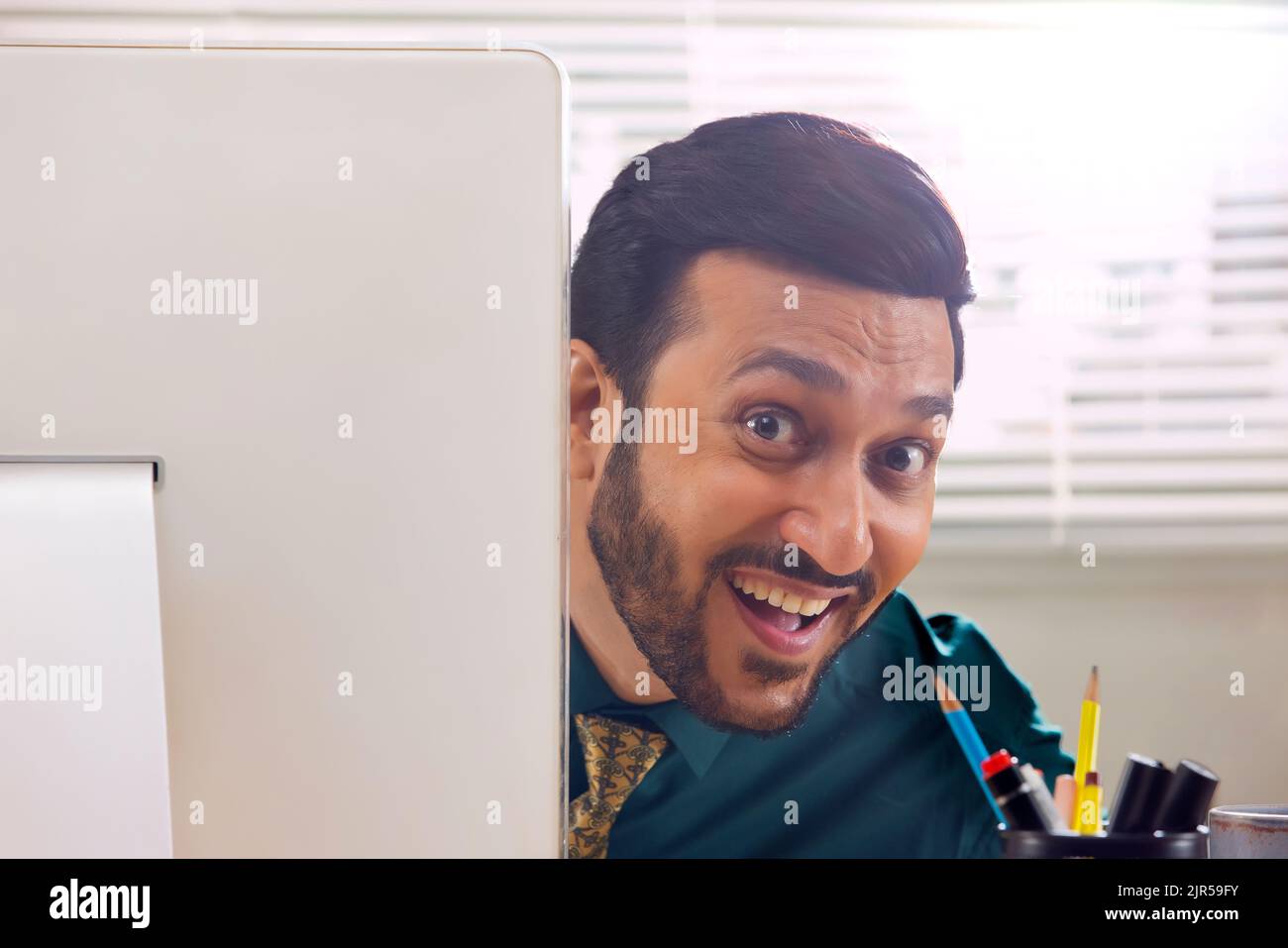 A corporate employee in formal clothing looking from behind desktop ...