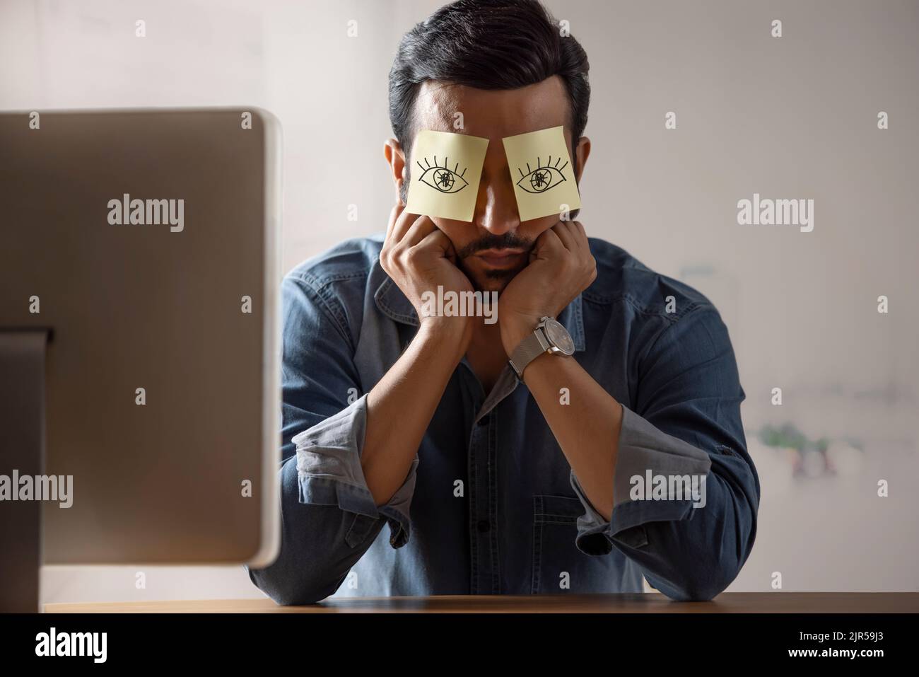 A corporate employee sitting with eyes covered with sticky notes in ...