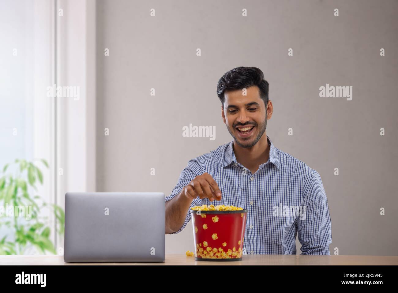 A happy corporate employee in formal clothing sitting with a laptop ...