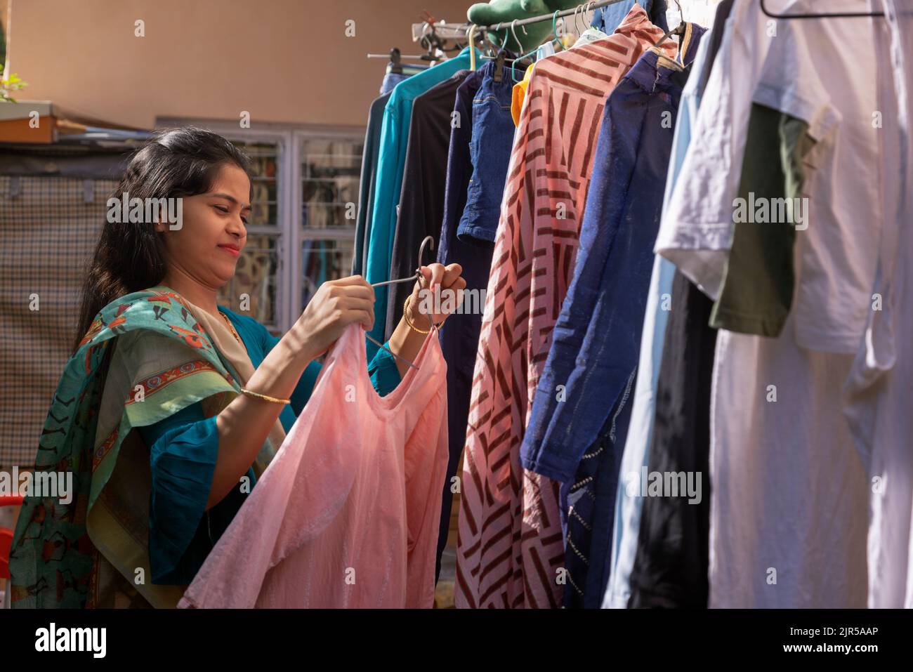 Young woman hanging clothes on washing line to dry outside Stock Photo ...
