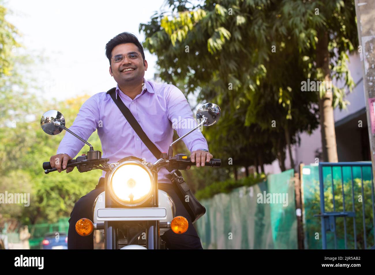 Portrait of cheerful young man riding on a motorcycle Stock Photo - Alamy