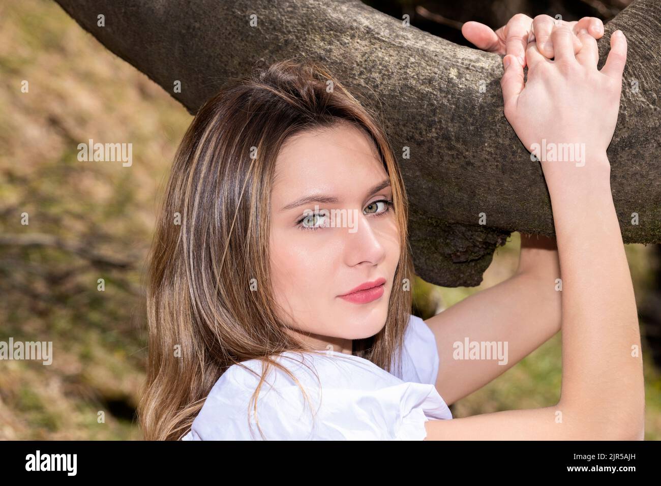 pretty blonde woman hugging a tree branch in a white dress Stock Photo ...