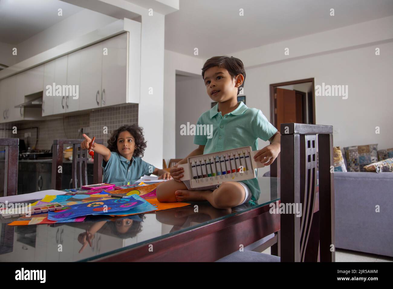 Younger brother holding up a set of tube painting colour while elder ...