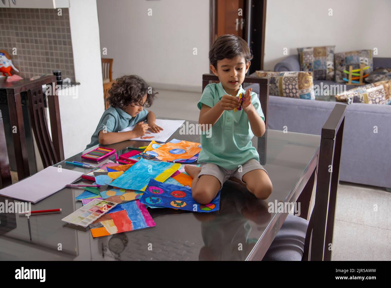 Younger brother playing with a toy car while elder brother painting on ...